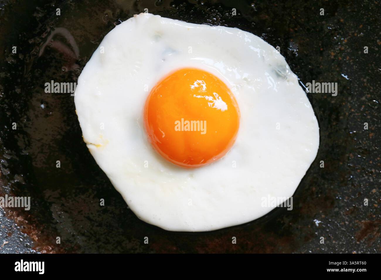 Top view of a sunny side up egg being fried in a pan Stock Photo - Alamy