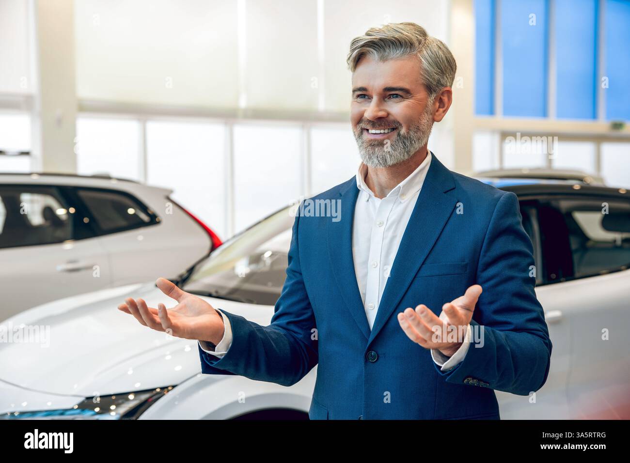 Professional salesman presenting new car in dealership showroom Stock ...