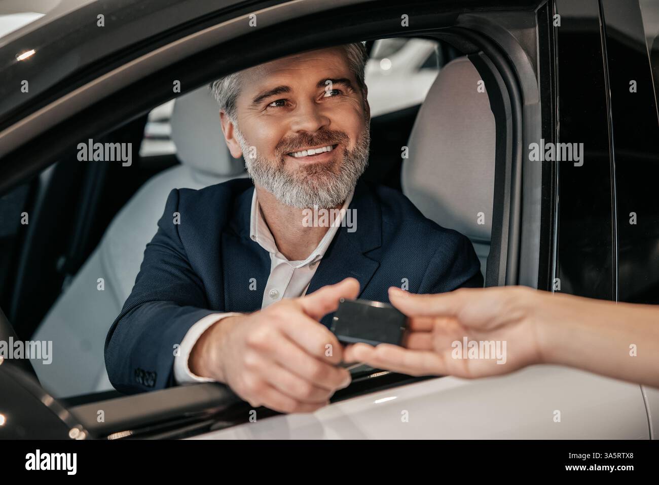 Man handing over keys to agent in car showroom Stock Photo - Alamy