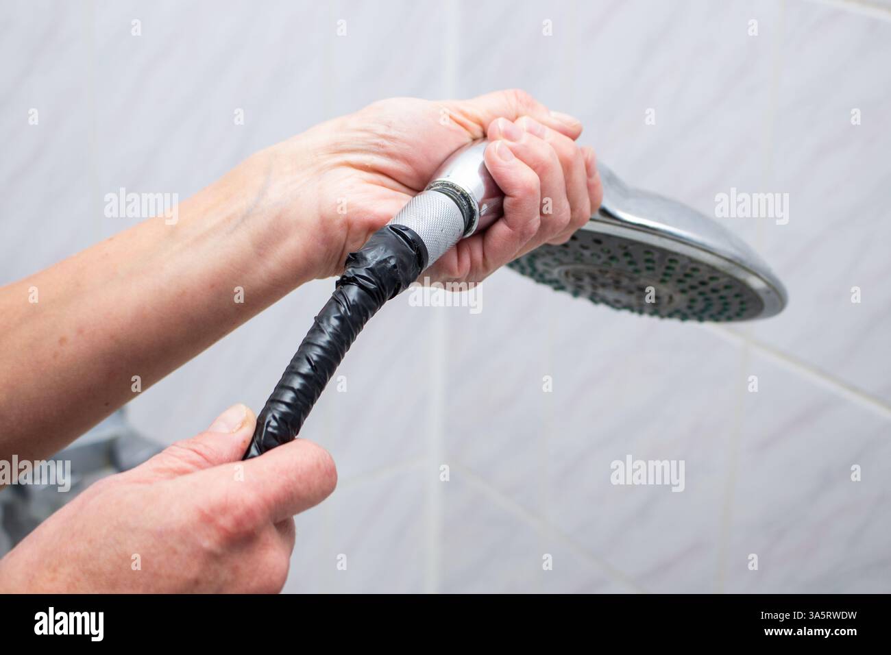 Woman changing broken shower hose in bathroom. Female plumber hands ...