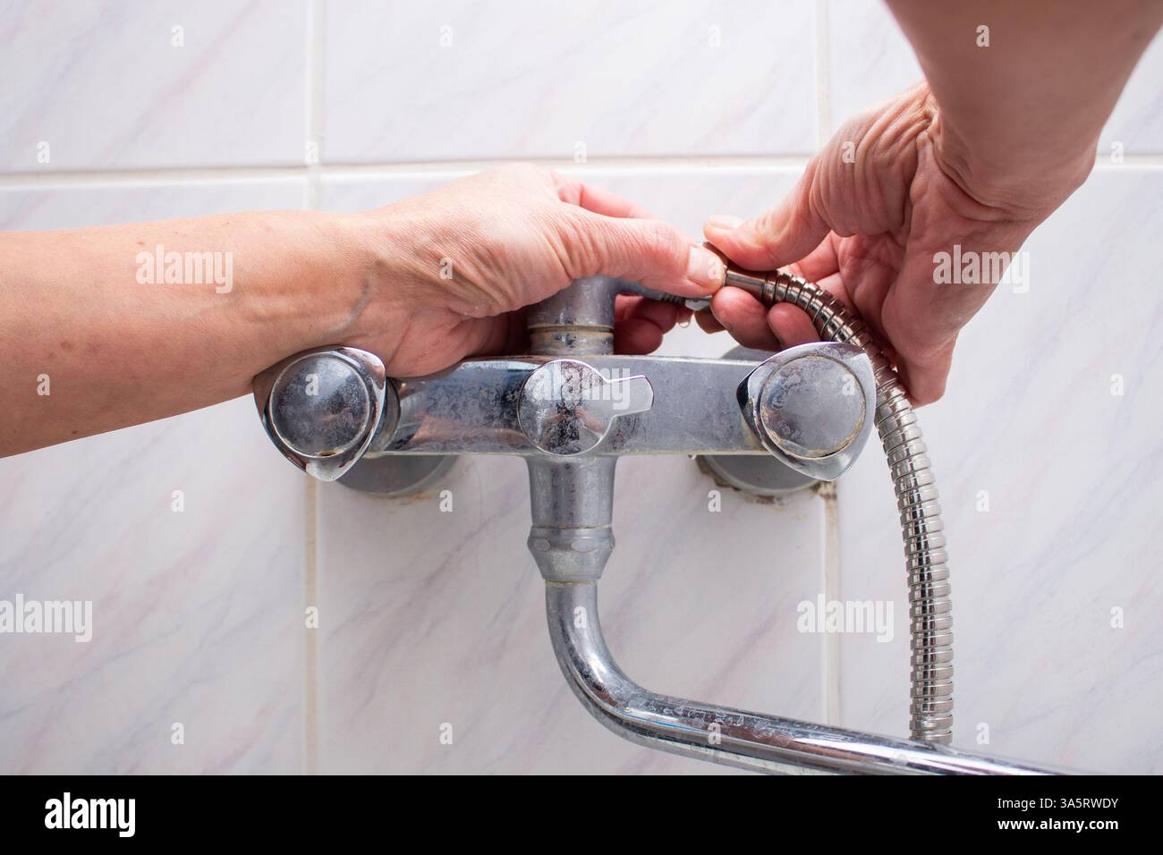 Woman changing broken shower hose in bathroom. Female plumber hands ...