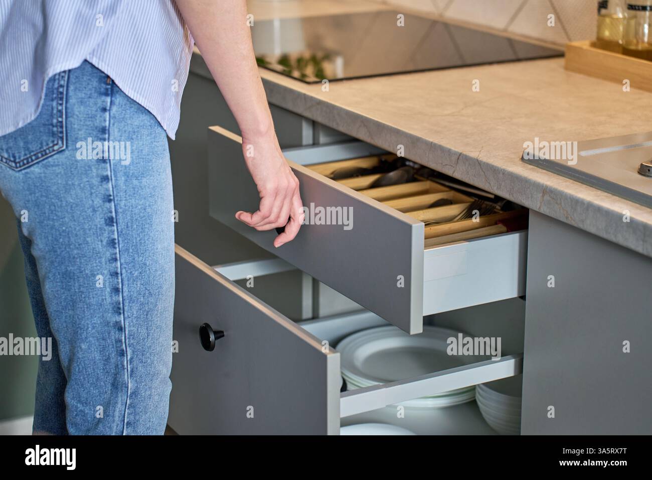 Person opens a kitchen drawer with various utensils in wooden cutlery ...
