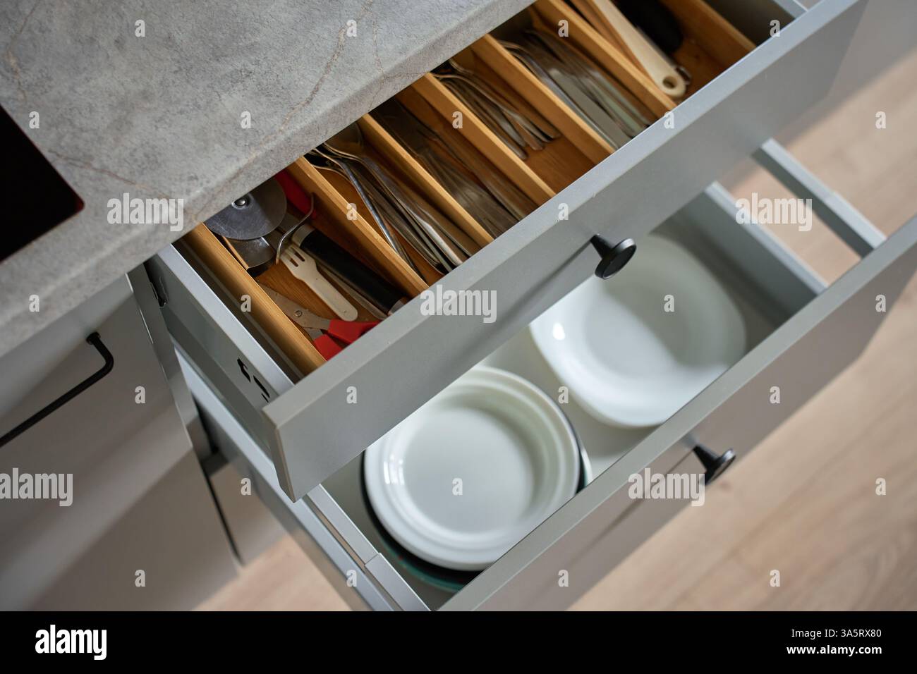 Modern kitchen with dishes and cutlery in open drawers. Contemporary ...