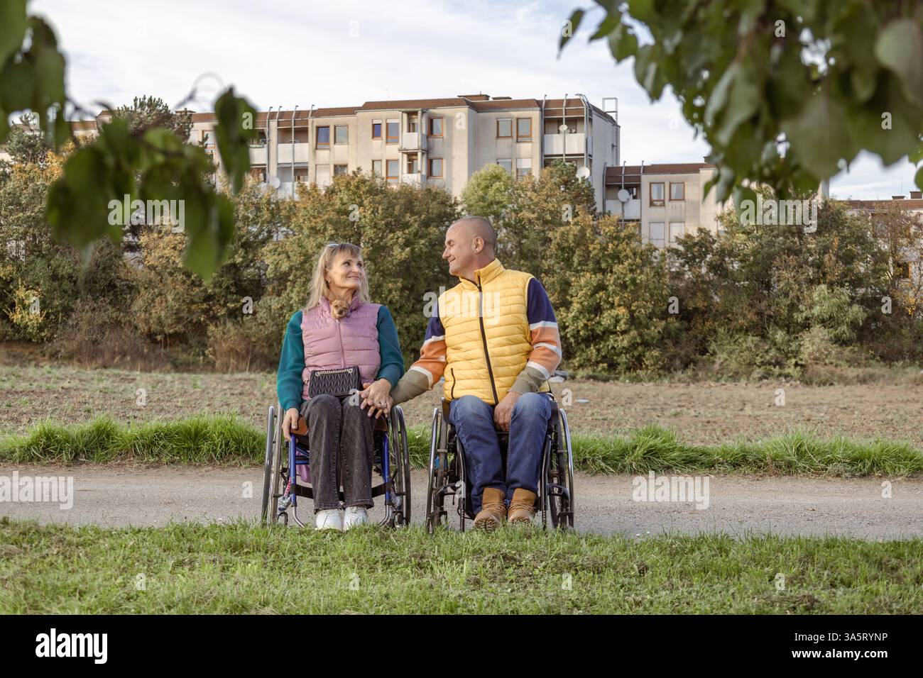 Two people with disabilities in wheelchairs are holding hands Stock ...