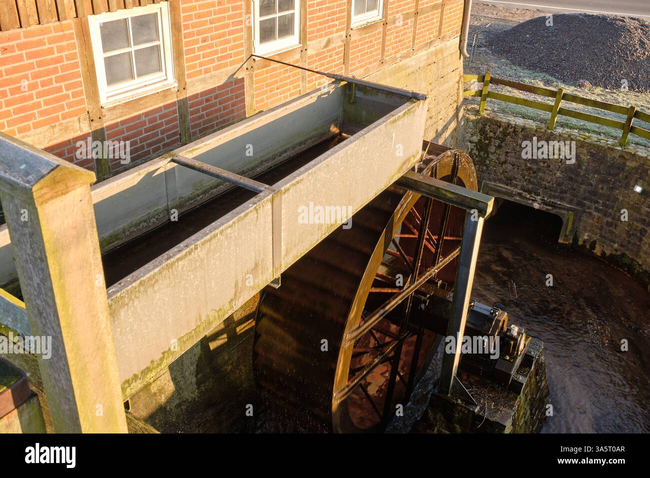 Overshot water wheel of a historic mill in morning light. Water flows ...