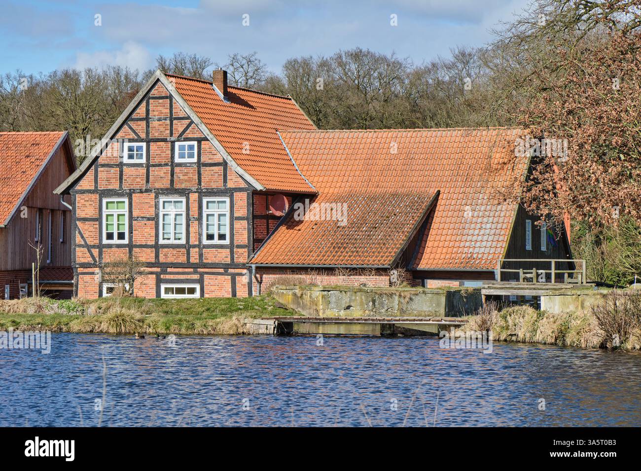 Historic half-timbered German watermill with red roof and reflection in ...