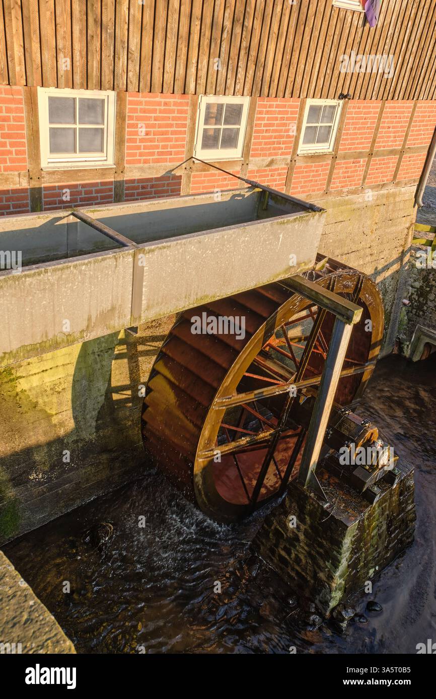 Overshot water wheel of a historic mill in morning light. Water flows ...