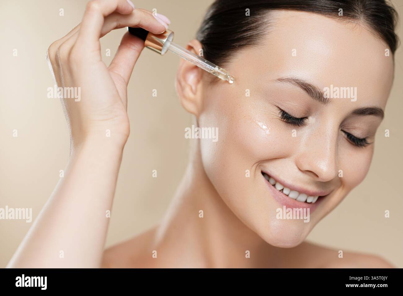 Positive woman applying hyaluronic serum on face in studio Stock Photo ...
