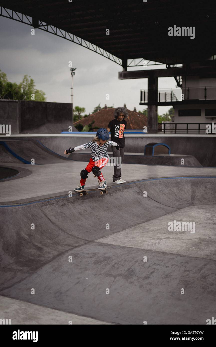 Instructor supporting boy on skateboard in skate park Stock Photo - Alamy