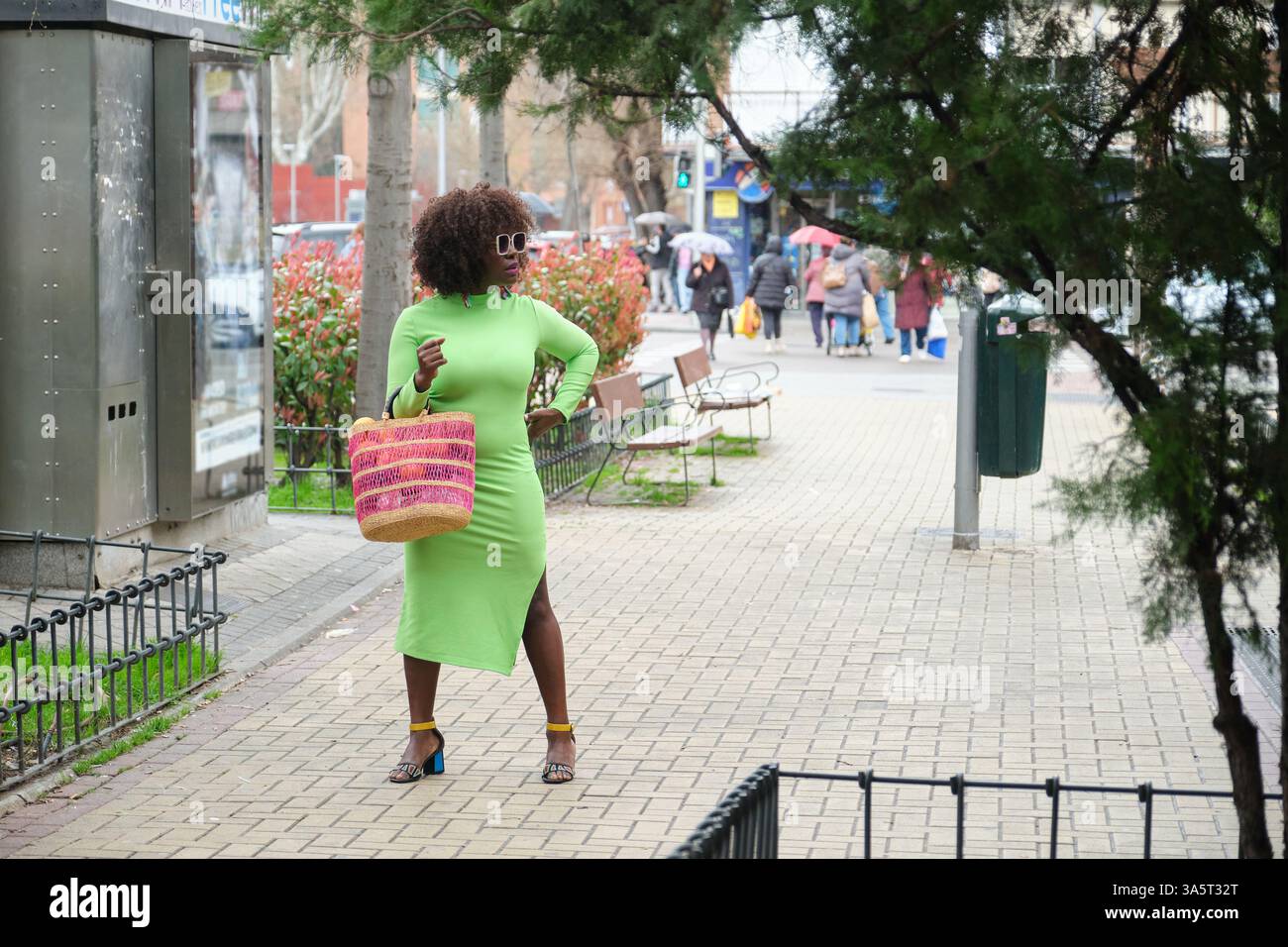Influencer posing with a straw bag and a green dress in urban street ...