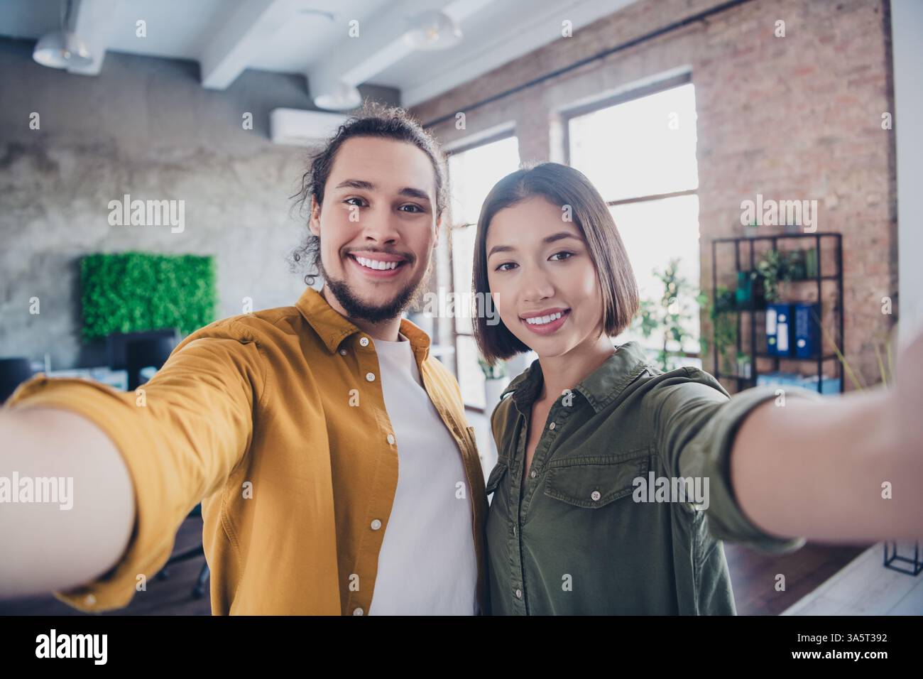 Cheerful young coworkers capturing a selfie in a modern coworking space ...
