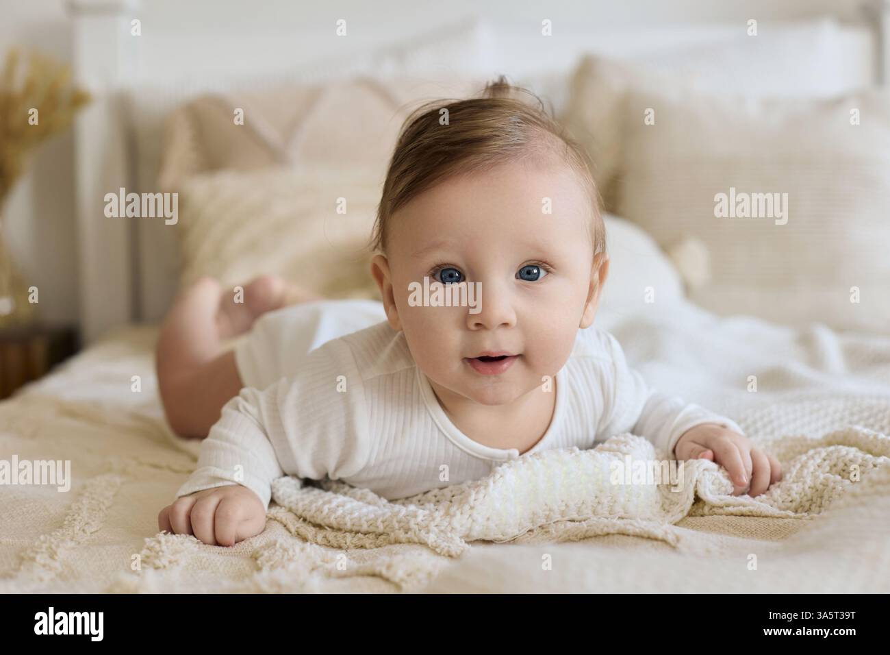 Adorable baby with blue eyes lying on a cozy bed Stock Photo - Alamy