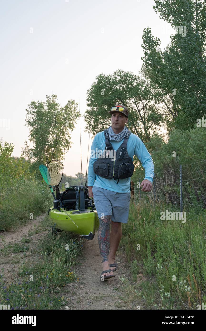 Man pulling kayak down to the water Stock Photo - Alamy