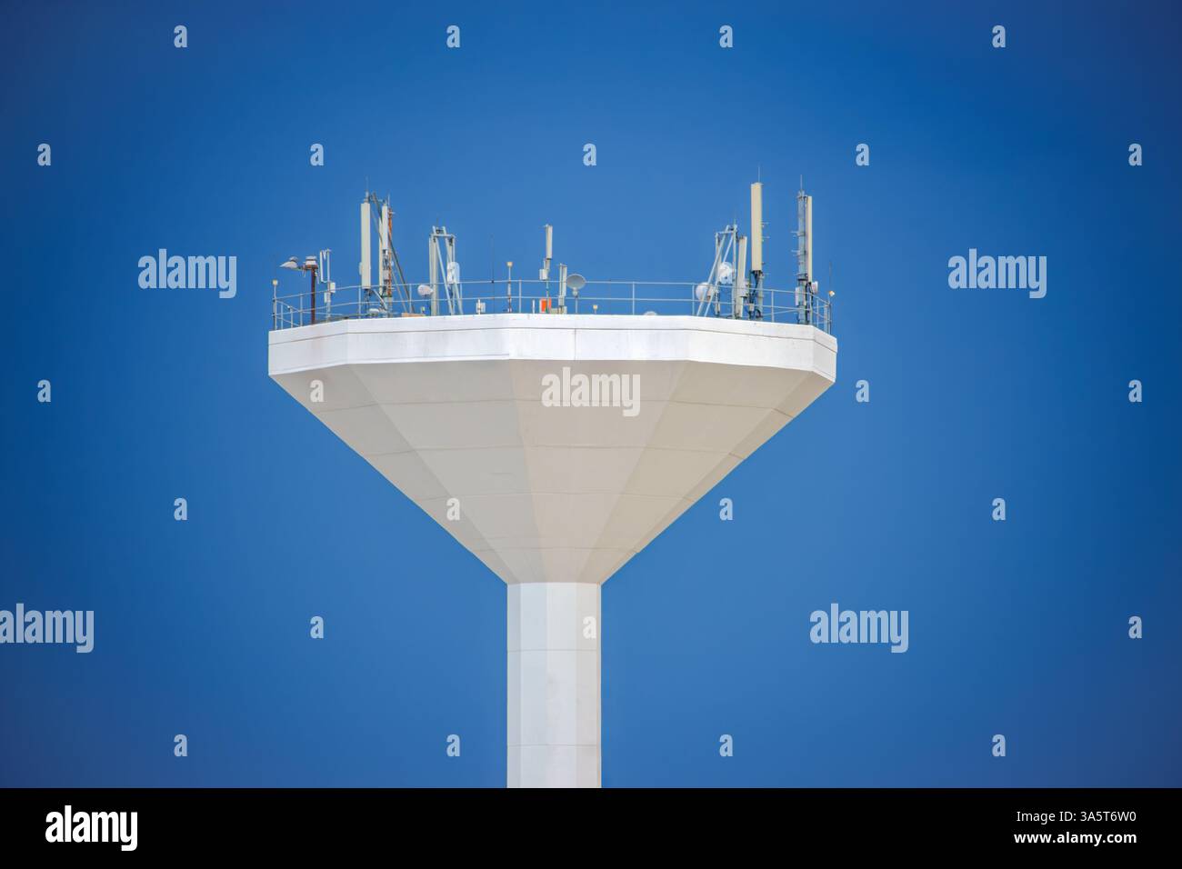 cellular antenna in top of water tower, white against the clear blue ...