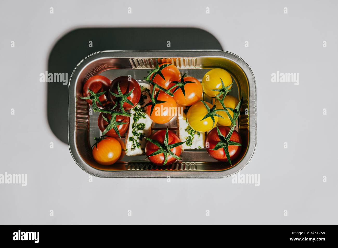 A tray of assorted tomatoes and cucumbers. The tray is silver and the ...