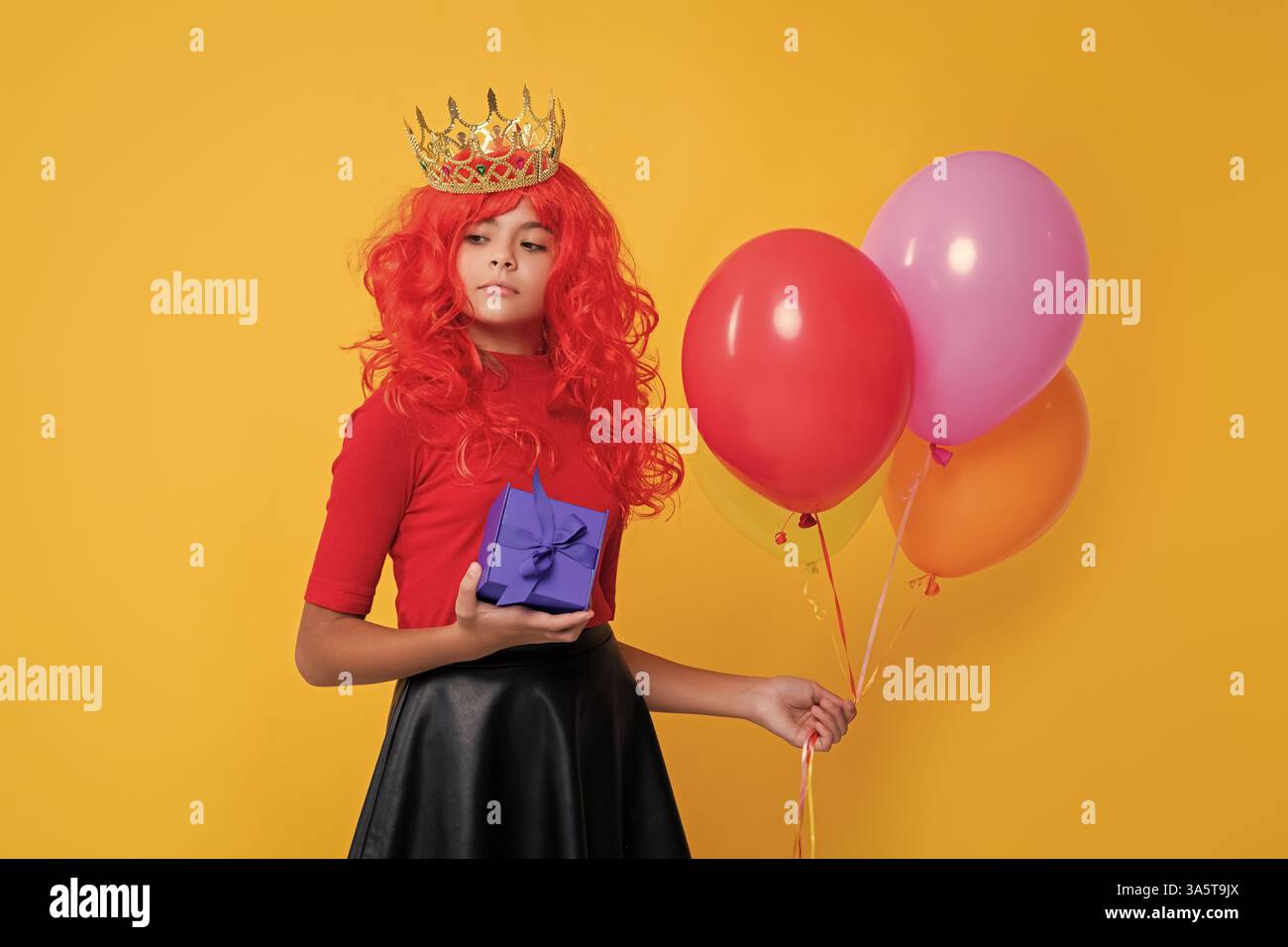 arrogant child in crown with gift box and party balloon on yellow ...