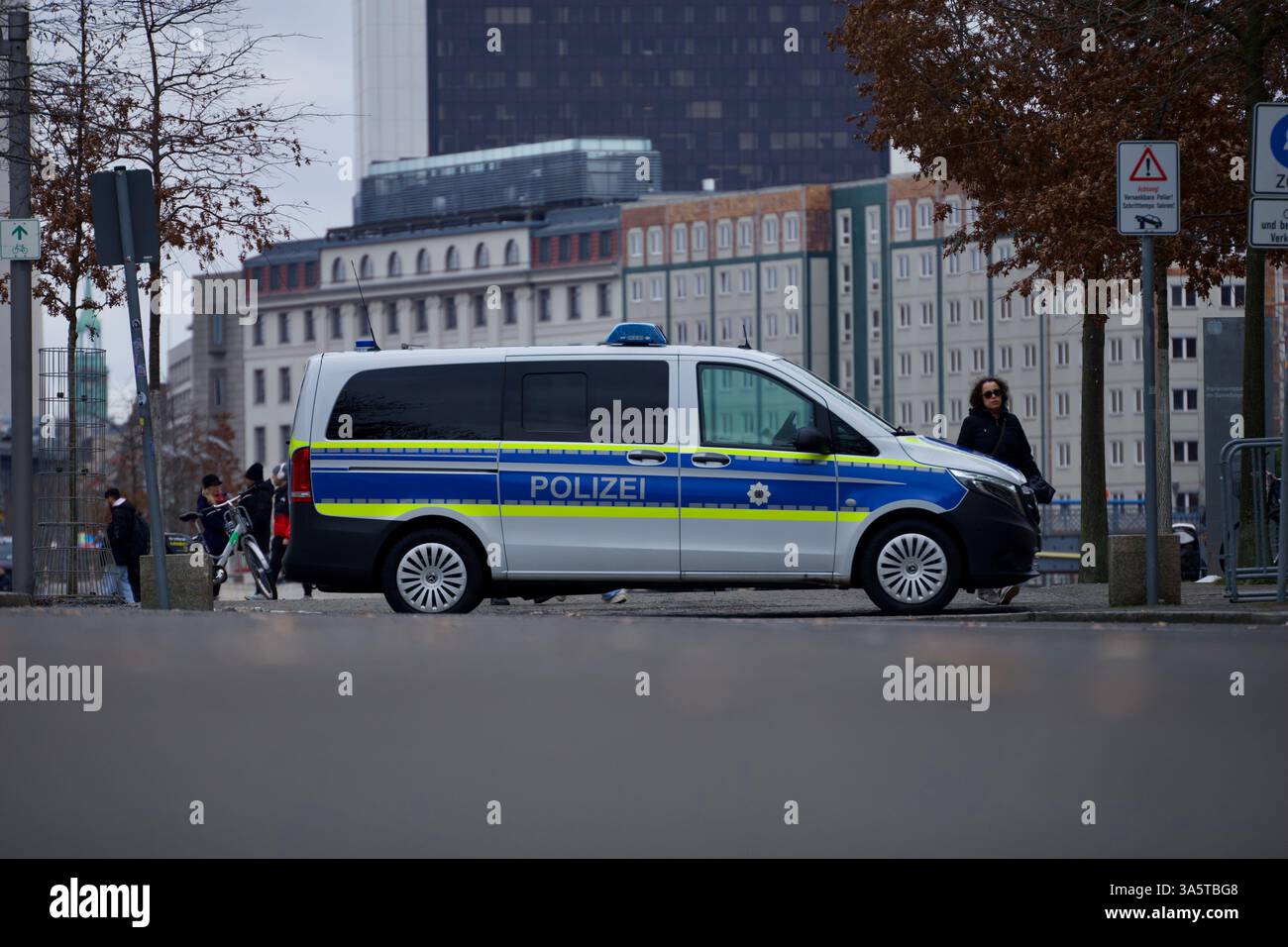 Berlin, Germany. February 23, 2025. A person walks by a police car in ...