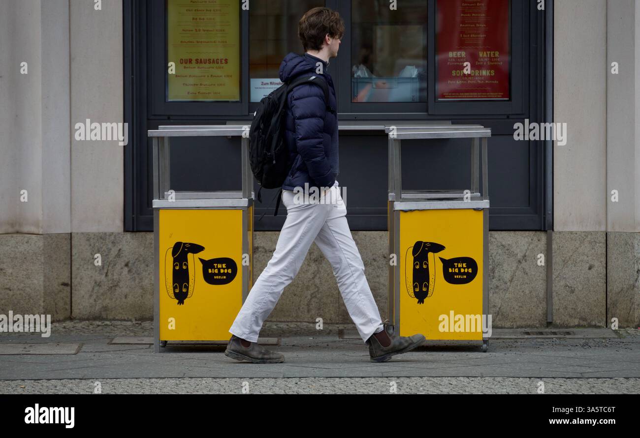 Berlin, Germany. February 23, 2025. A person walks by a sausage ...