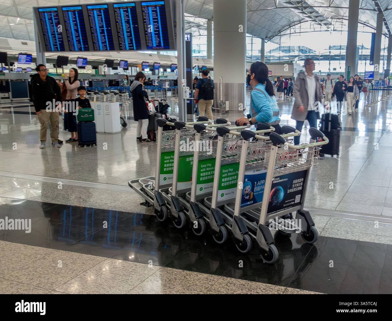 A staff member is seen pushing trolleys in the departure hall at Hong Kong International Airport ...