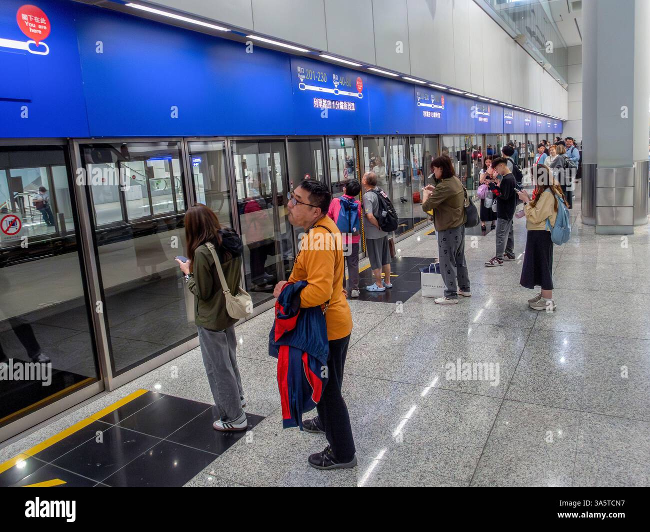 Hong Kong, China. 23rd Mar, 2025. Passengers are seen waiting to board the train in the ...