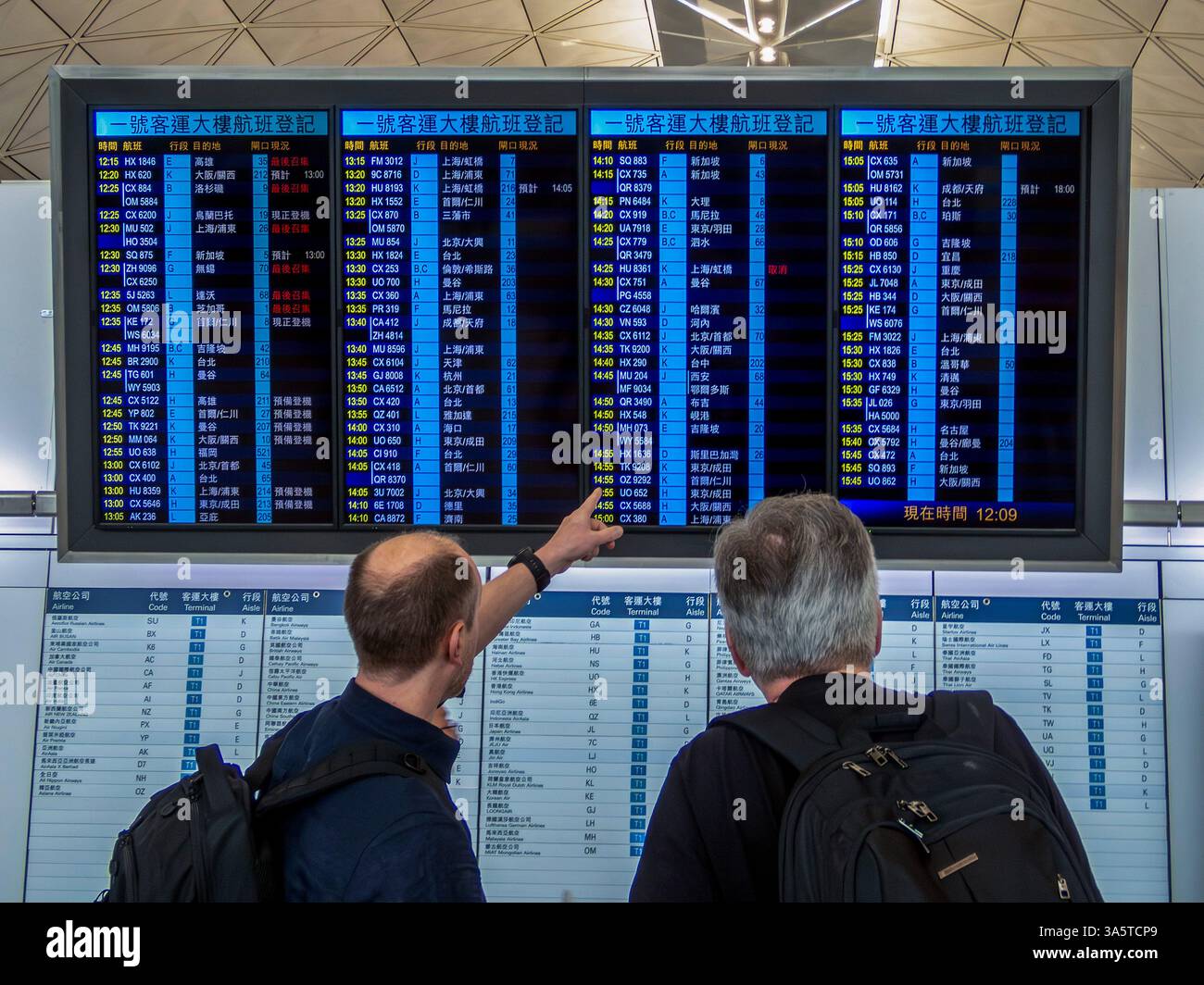 Hong Kong, China. 23rd Mar, 2025. Passengers are seen looking at the departure flight schedule ...