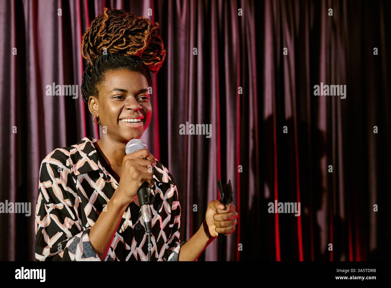 African American woman smiling and holding microphone while on stage ...