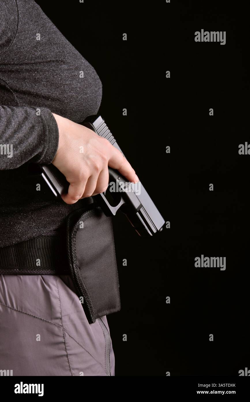 Close up side view of hand with a gun pulled from holster on a black ...