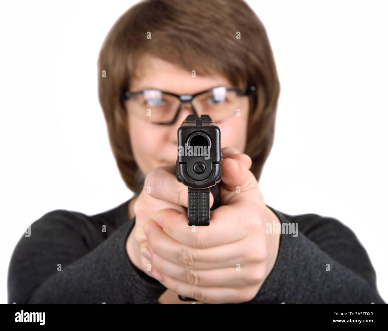 Woman pointing a gun at the camera on a white background. Focus on the ...
