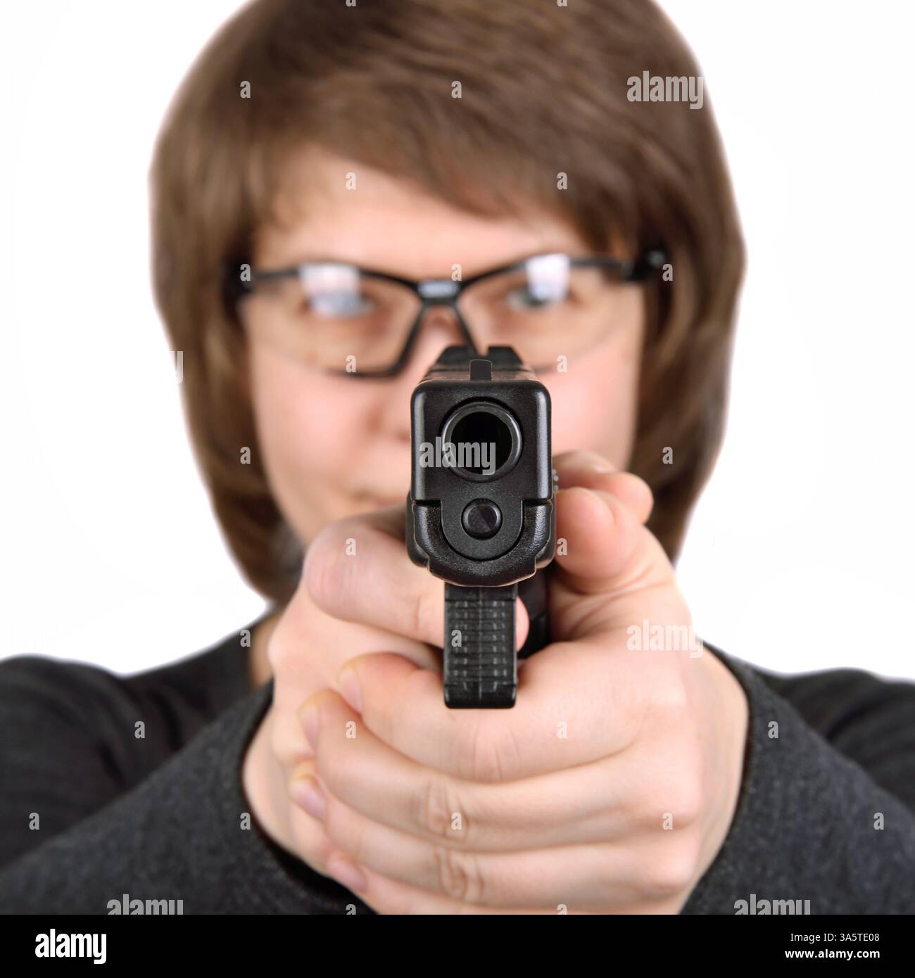 Woman pointing a gun at the camera on a white background. Focus on the ...