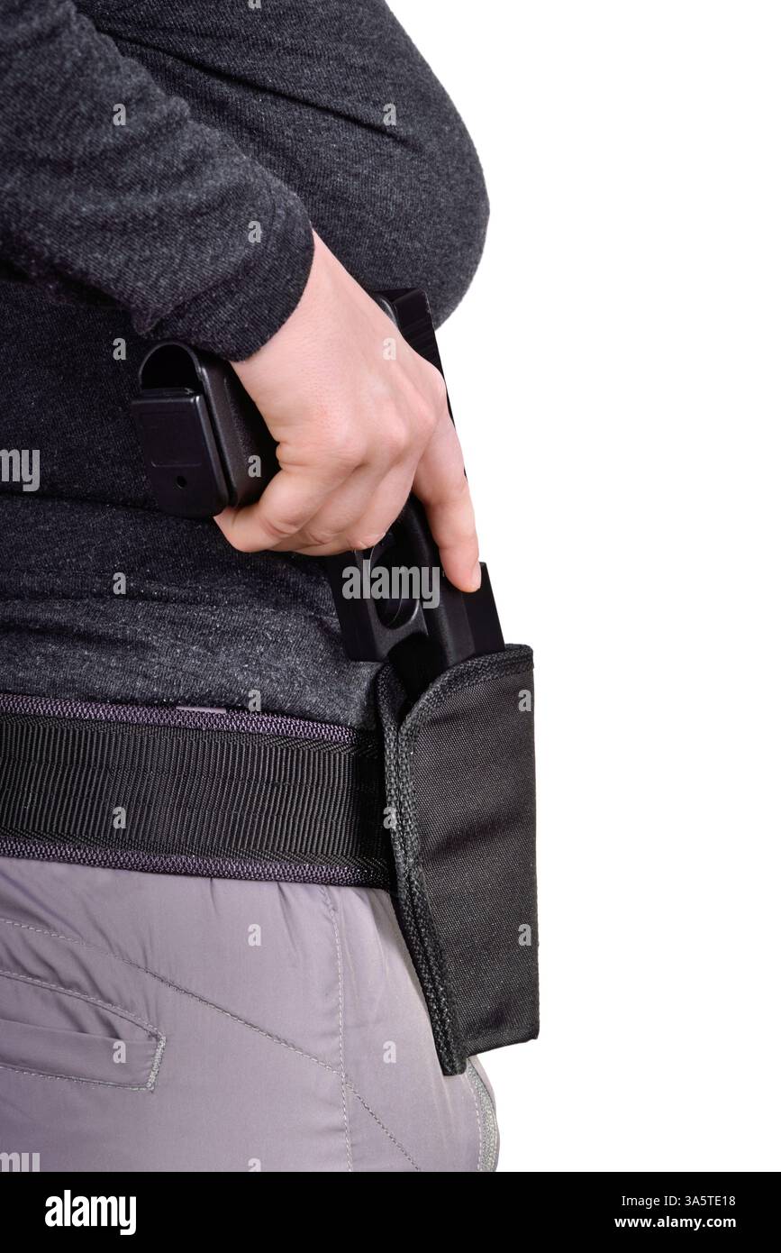 Close up side view of womans hand puts the gun in the holster on a ...