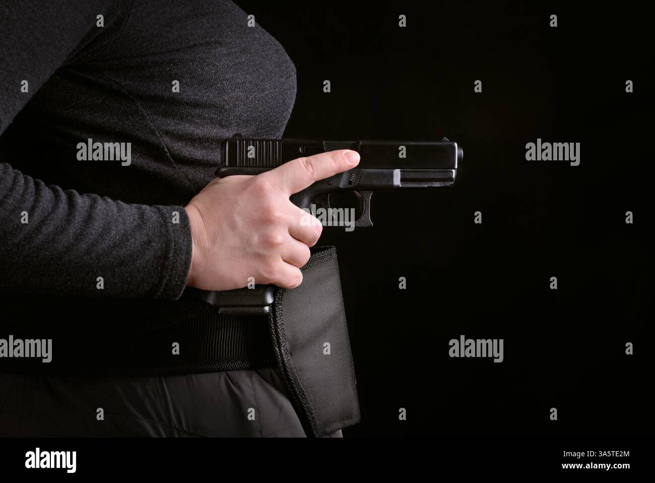 Close up of woman hand with gun pulled from the holster on black ...