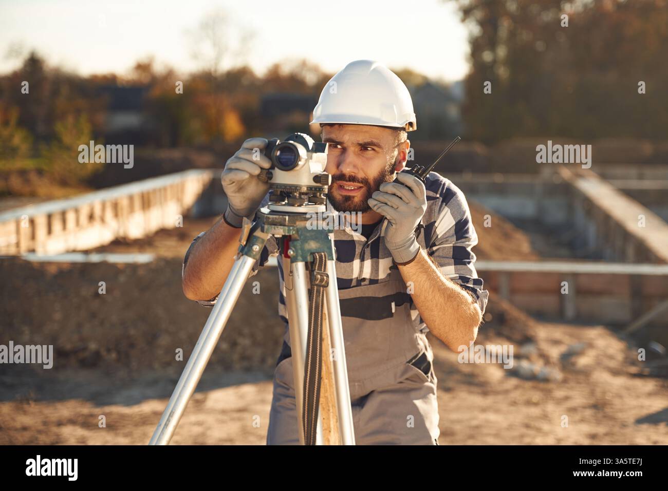 Front view, using geodetic optical level. Worker is on the construction ...