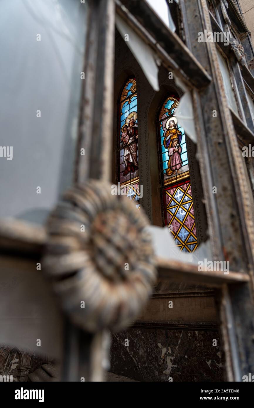 Colorful stained glass seen through a broken mausoleum window ...