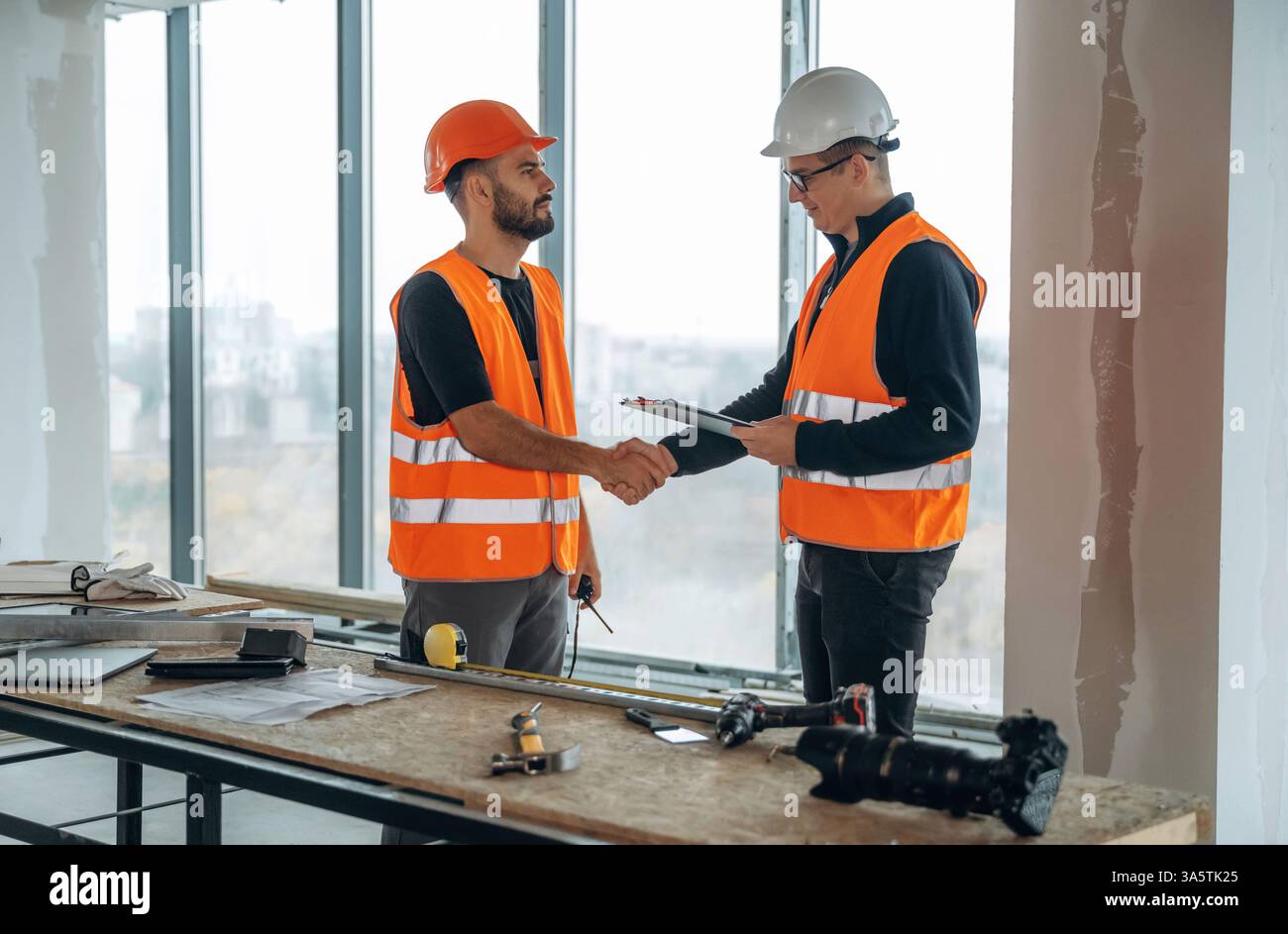 Greetings handshake. Two construction workers are in the unfinished room together Stock Photo ...