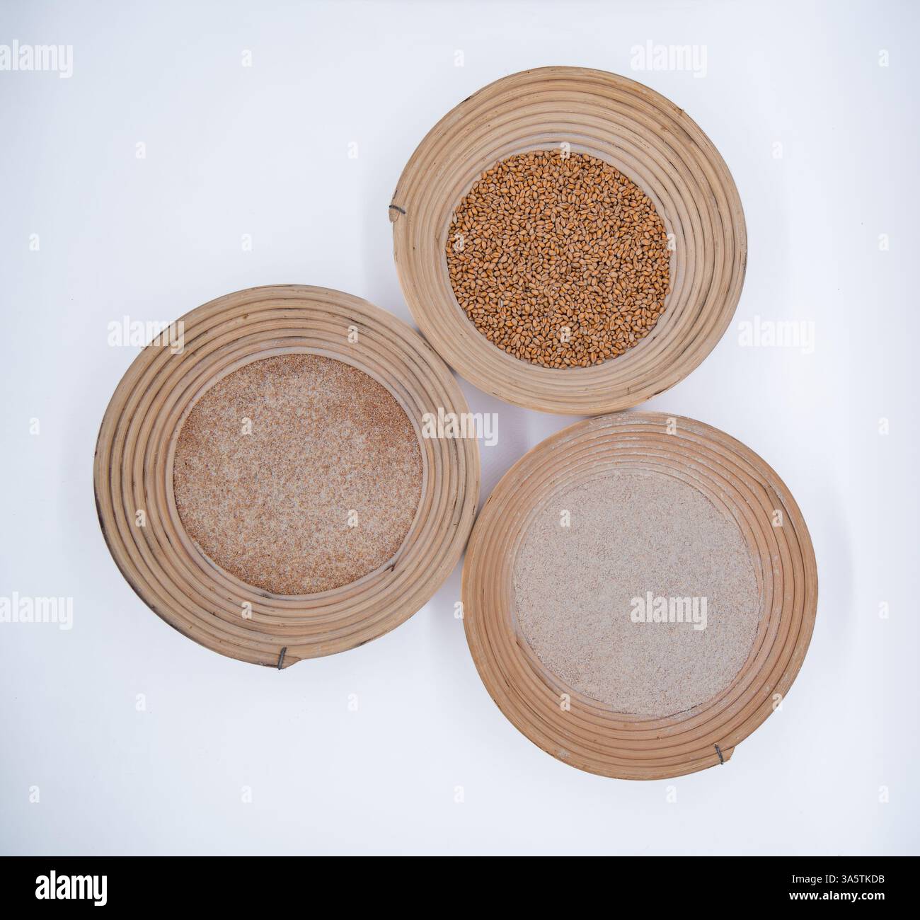 Three round wooden bowls filled with grains and wheat, arranged in a ...