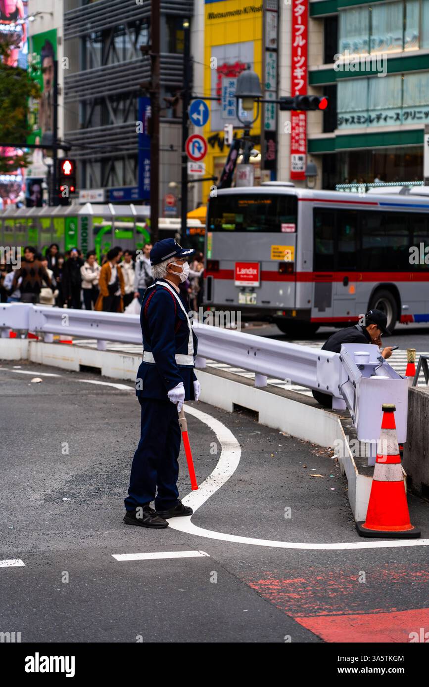 Police officer guiding pedestrians at the busy Shibuya Crossing, Tokyo ...