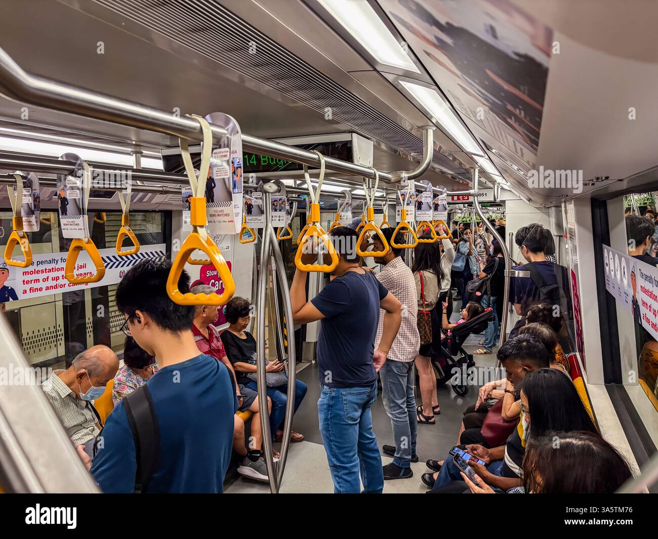 Singapore Mass Rapid Transit (MRT) train car full of commuters on the move. View of the interior ...