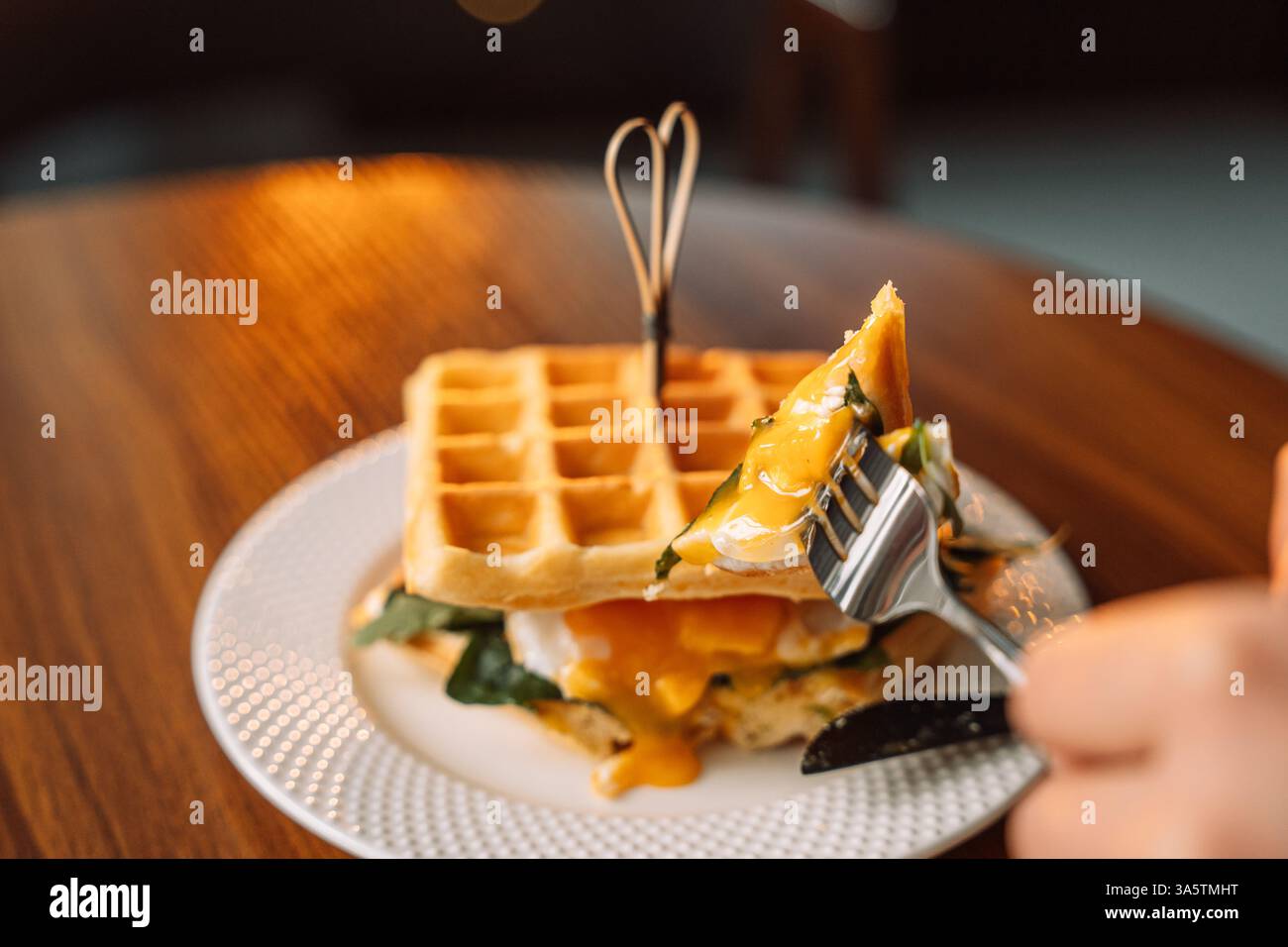 Breakfast homemade belgian waffle sandwich with egg, fork in hand Stock ...