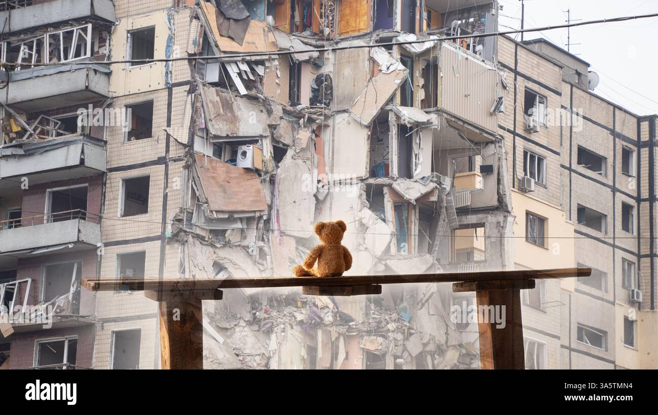 A teddy bear sits on a bench against the backdrop of a house blown up ...