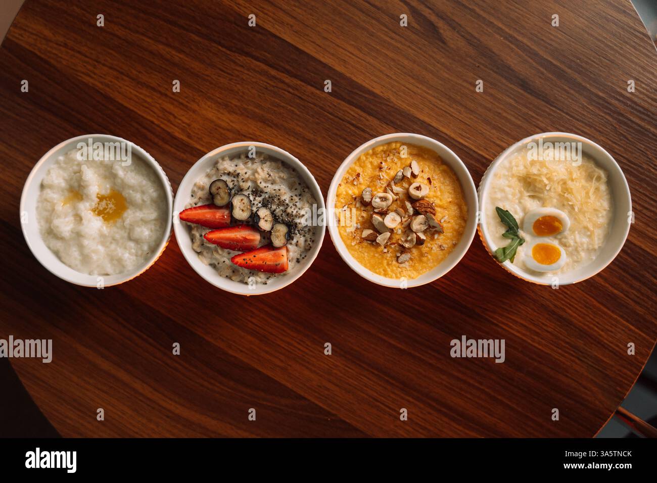 4 types of porridge in white bowls on a wooden background, oatmeal, corn, millet and rice Stock ...