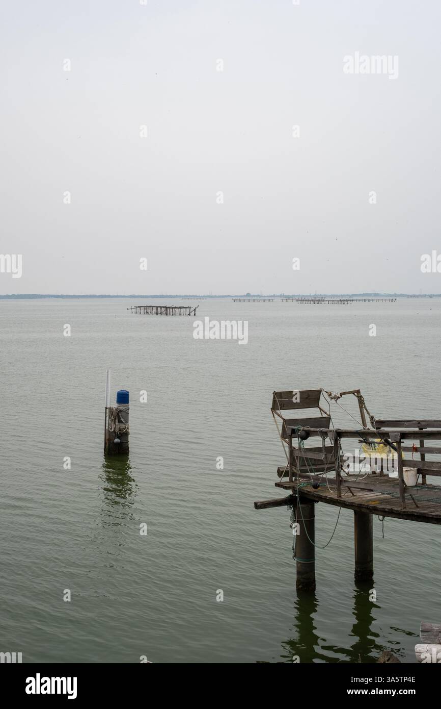 Old wooden fishing platform by the lagoon with aquaculture structures ...