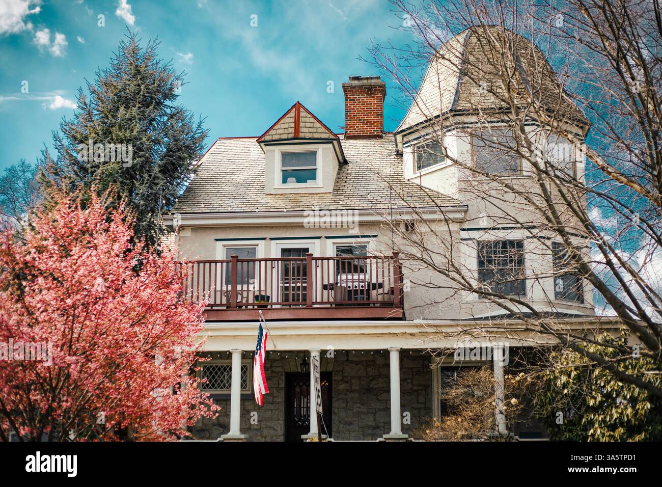 A charming house with a turret roof is surrounded by bright pink cherry ...