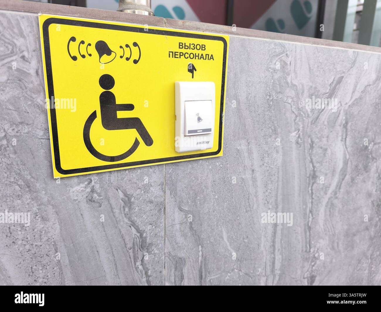 Yellow accessible assistance sign with bell symbol on grey marble wall ...
