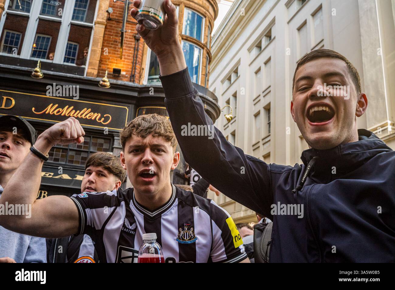 A Newcastle United fan raises his beer as another playfully flexes his ...