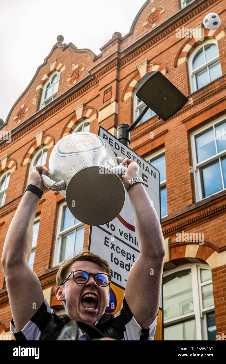An excited supporter holds an inflatable trophy above his head in ...