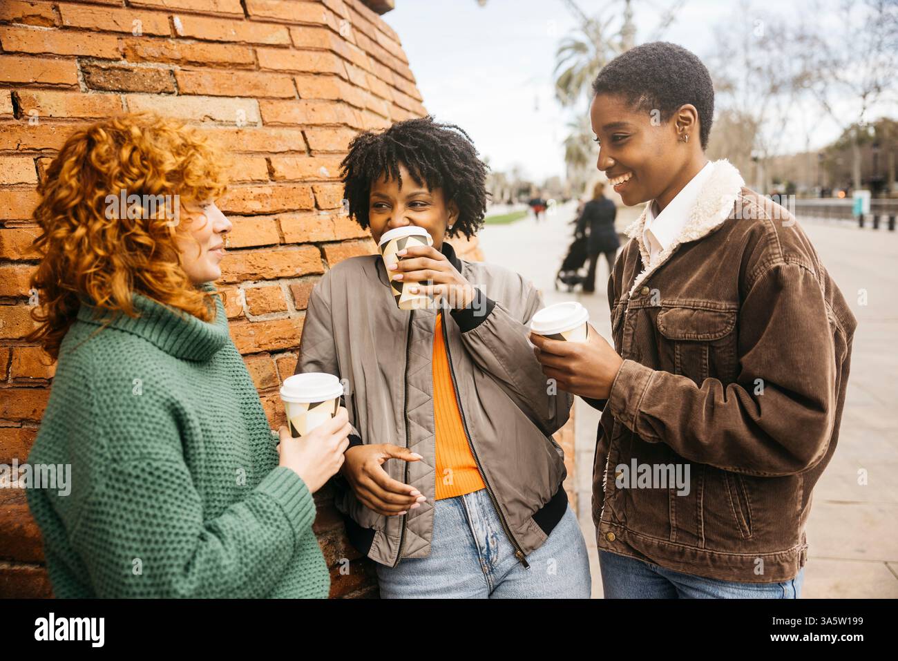 Three female tourists are enjoying a coffee break, chatting and laughing together during their ...