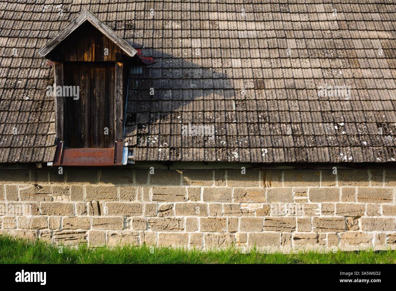 Minimalist photo of a stone country house with an old gray roof and a ...