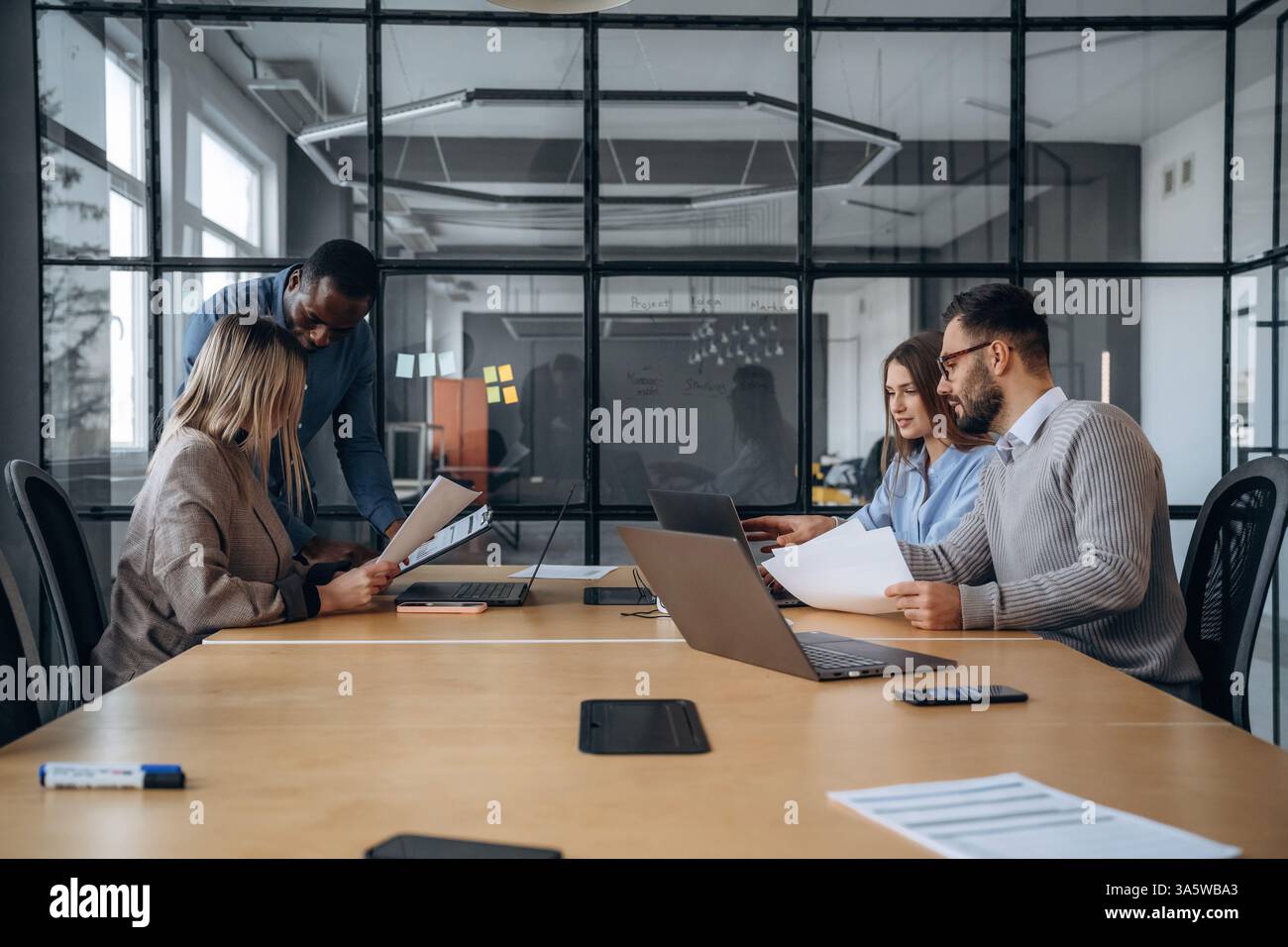 Calm, sitting by the table. Professional workers are in the modern ...