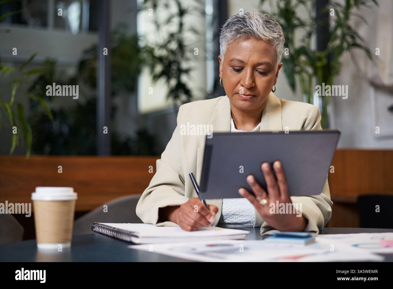 Professional Businesswoman Reviewing Digital Tablet While Taking Notes ...