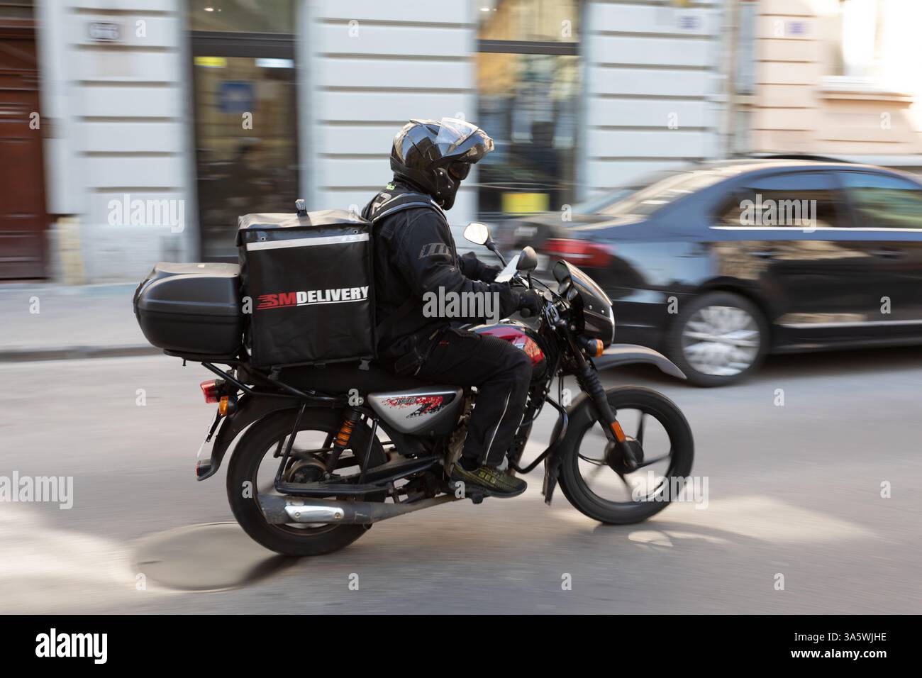 Lviv, Ukraine - Mar. 22, 2025: A food delivery rider speeds through the ...